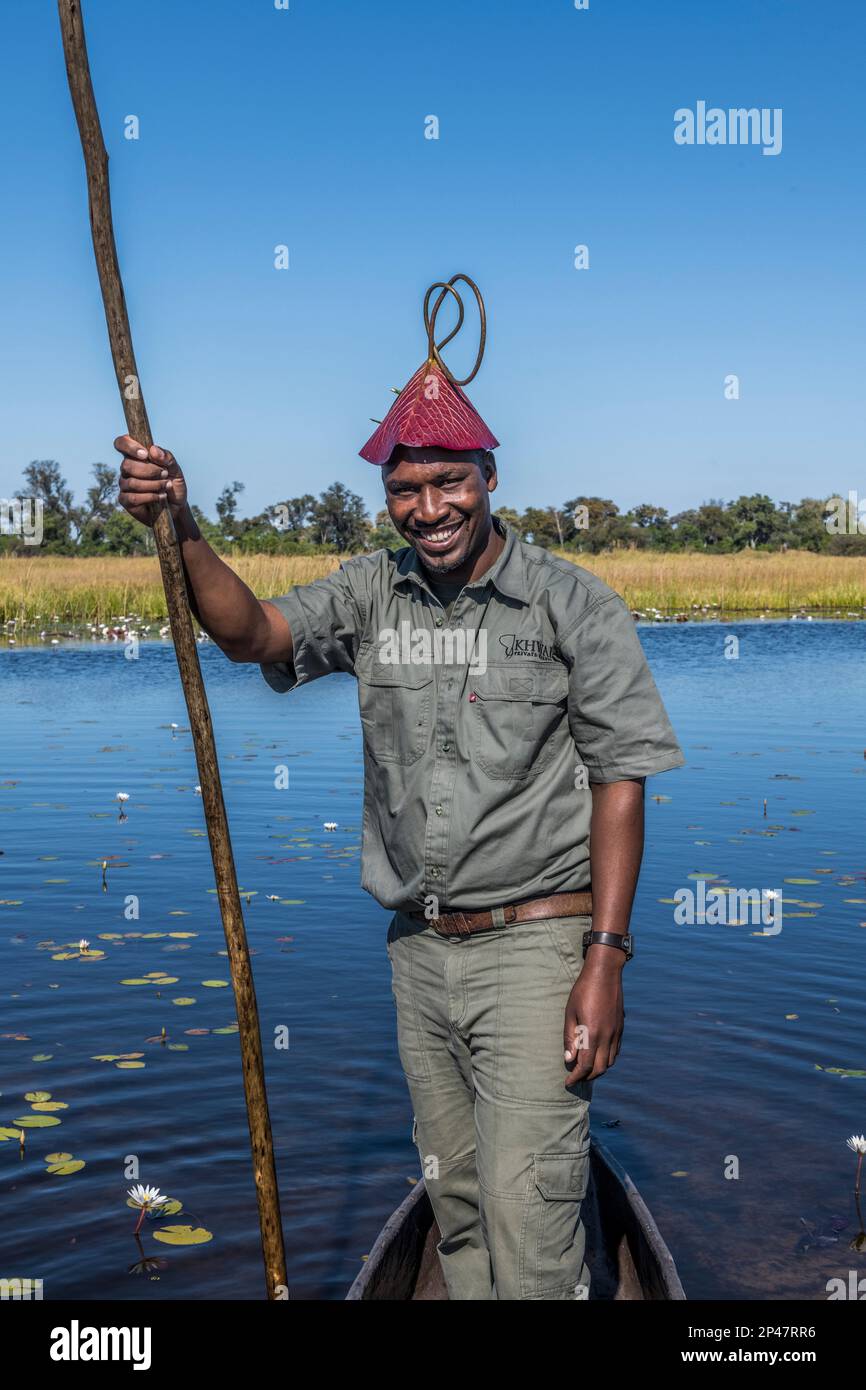 Africa, Botswana, Okavango Delta. A guide navigates the river on a ...