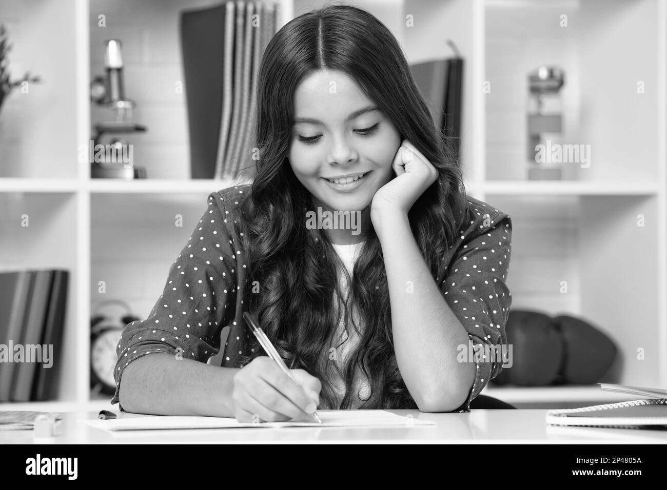 School student writing in exercise book, studying in classroom. Happy ...