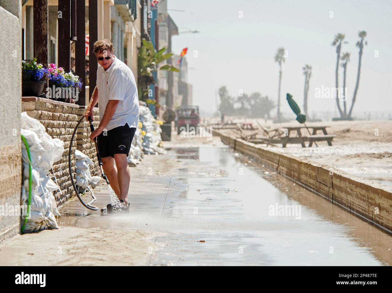 John Breiding washes sand from the boardwalk in front of his beachfront ...