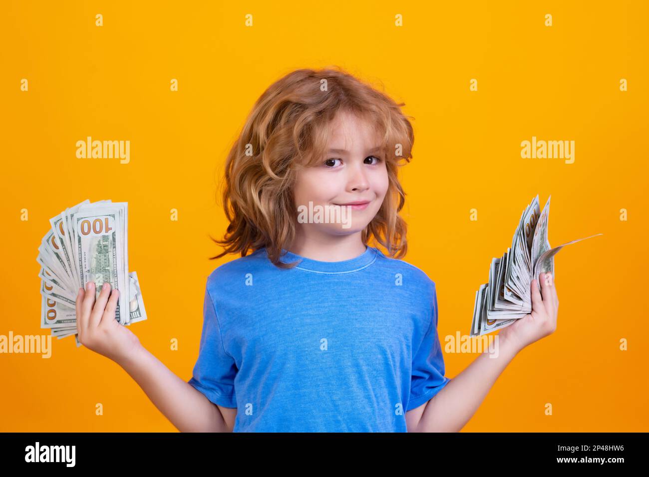 Child with lots of money dollar banknotes isolated over yellow studio ...