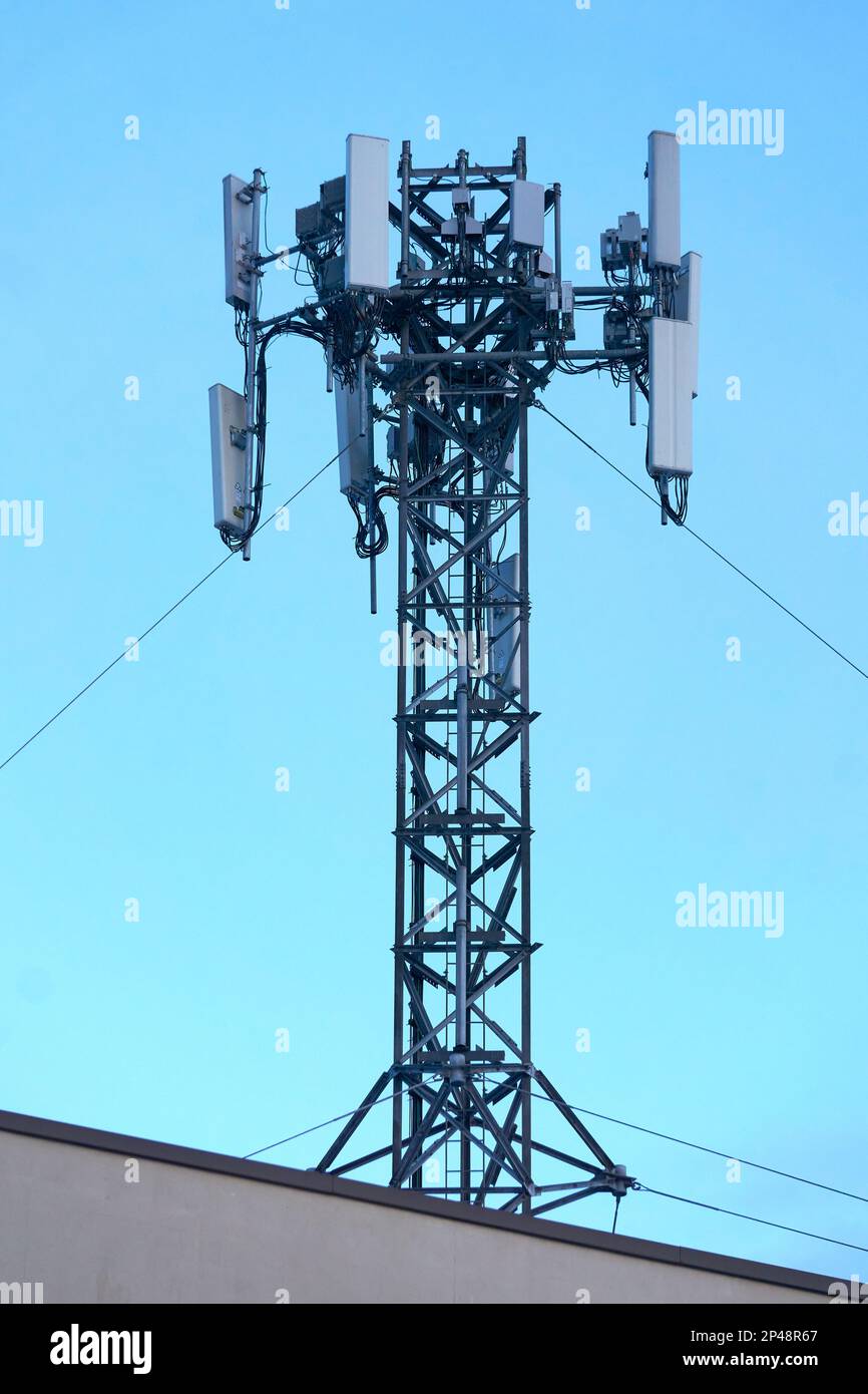 Closeup of a cell phone tower on the roof of a building against a blue ...