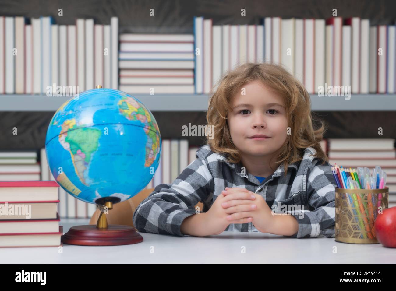 Pupil looking at globe in library at the elementary school. Back to ...