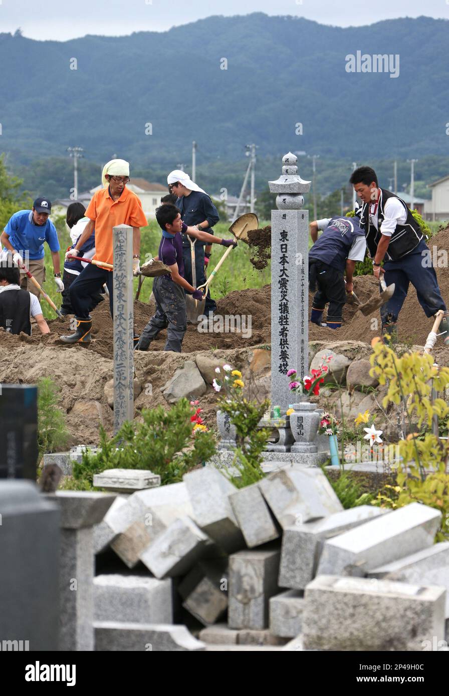 Volunteer workers use a sand sieving tool to find human bones, which ...