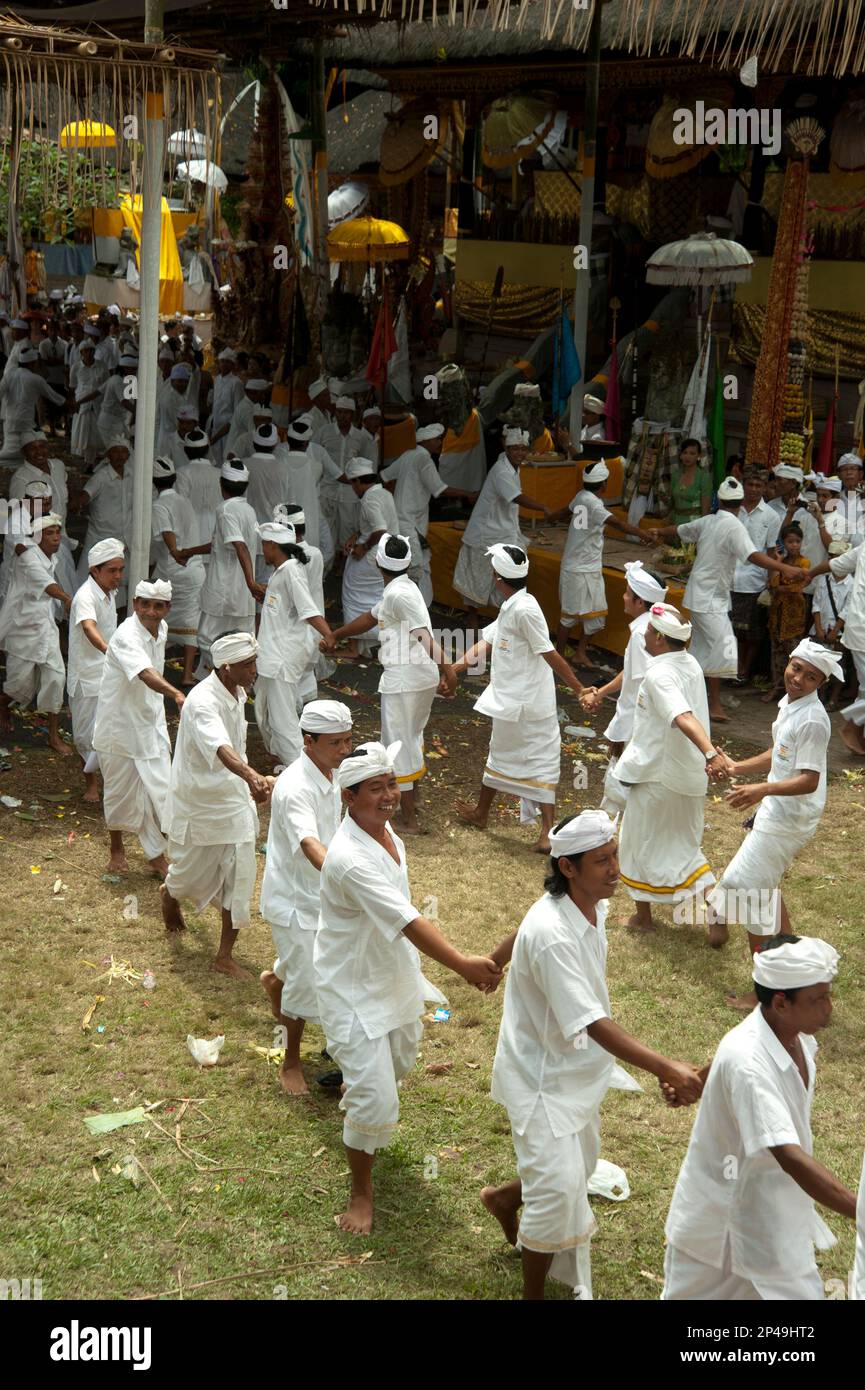 Men holding hands in procession during Siat Sampian (coconut leaf war ...