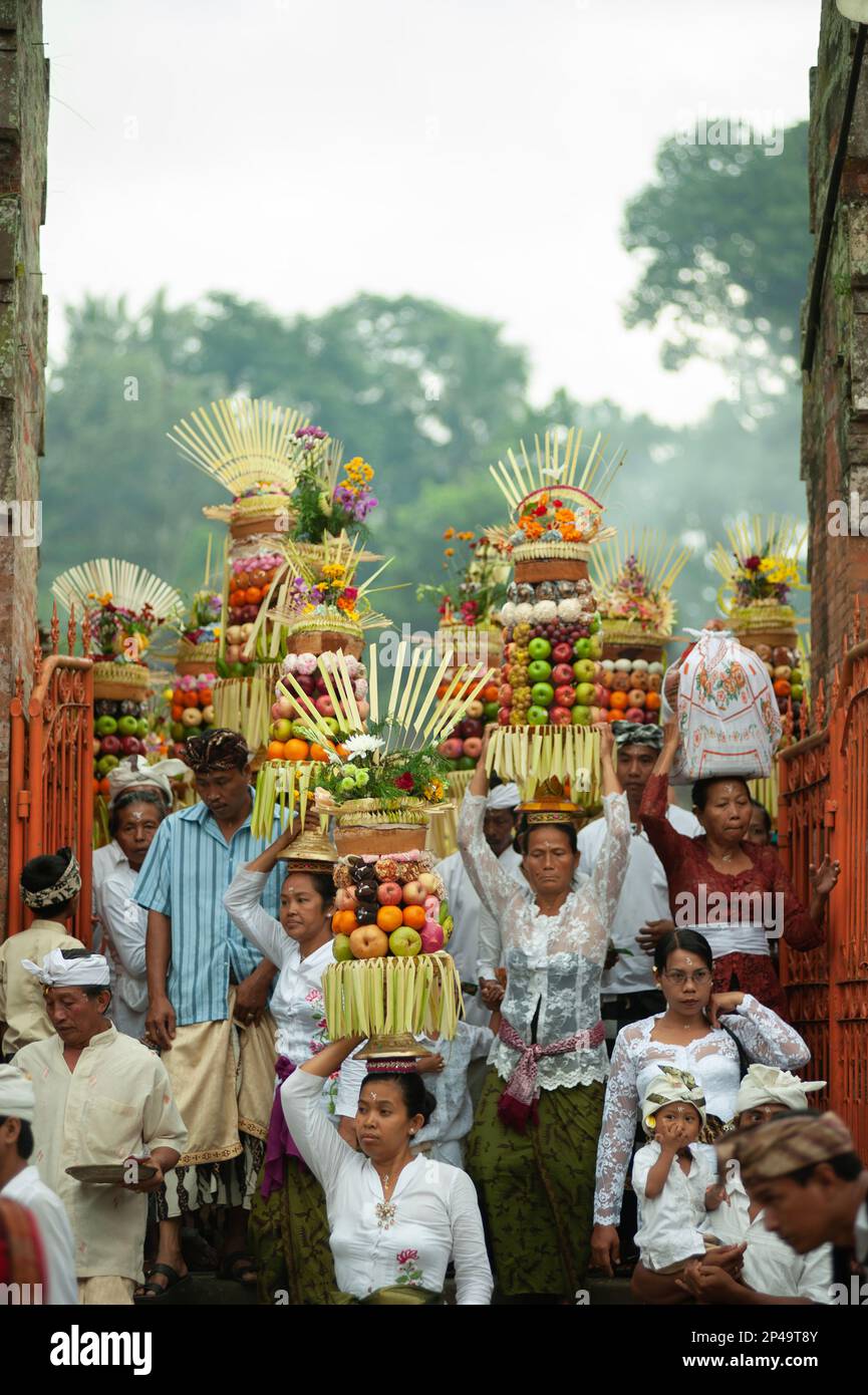 Women in procession carrying fruit offerings entering temple through ...
