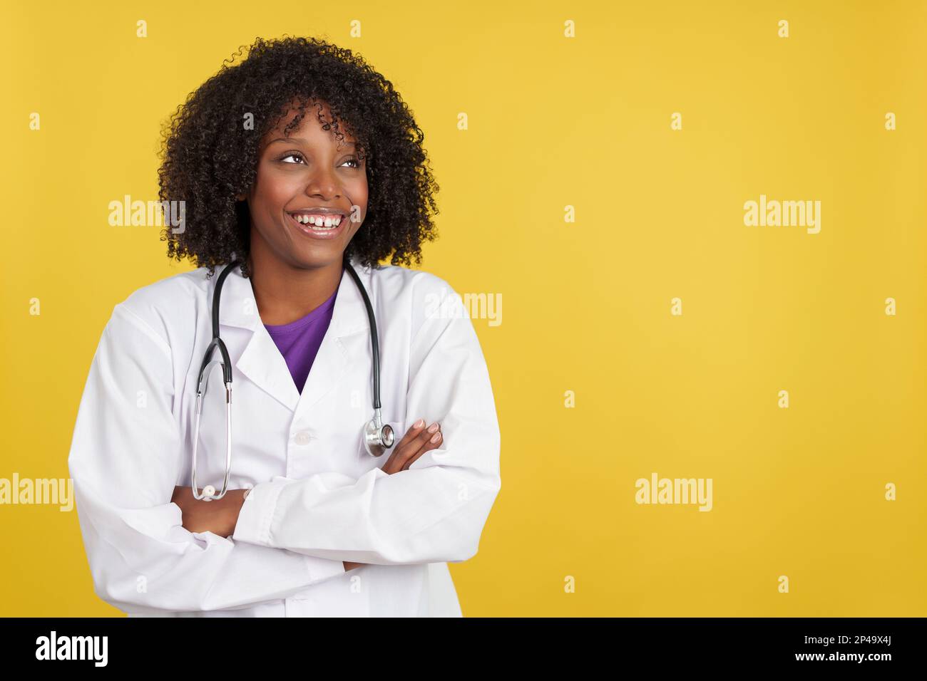 Happy doctor with afro hairstyle smiling standing with arms crossed ...