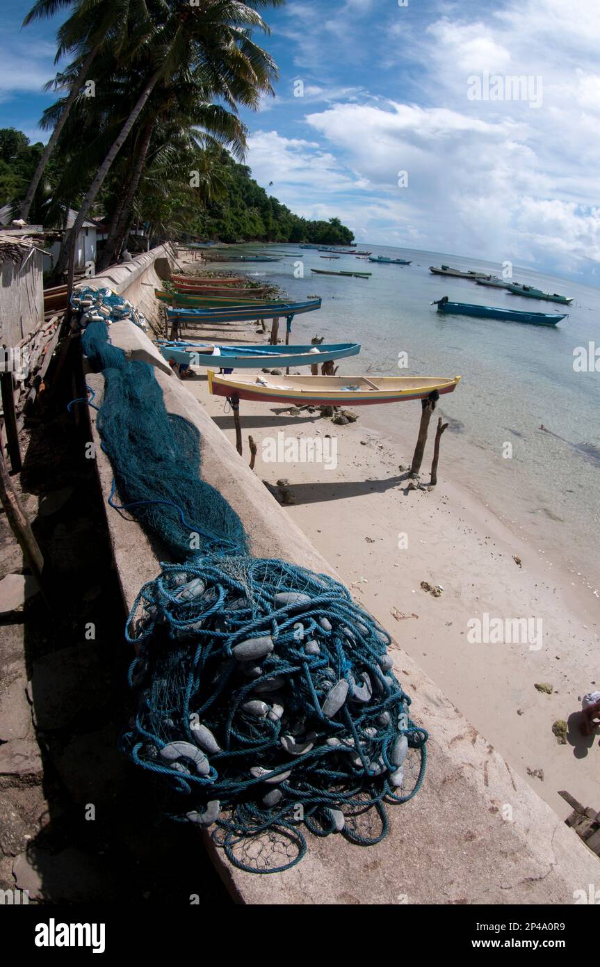 Fishing net on wall and boats on stilts on beach, Run Island, near ...
