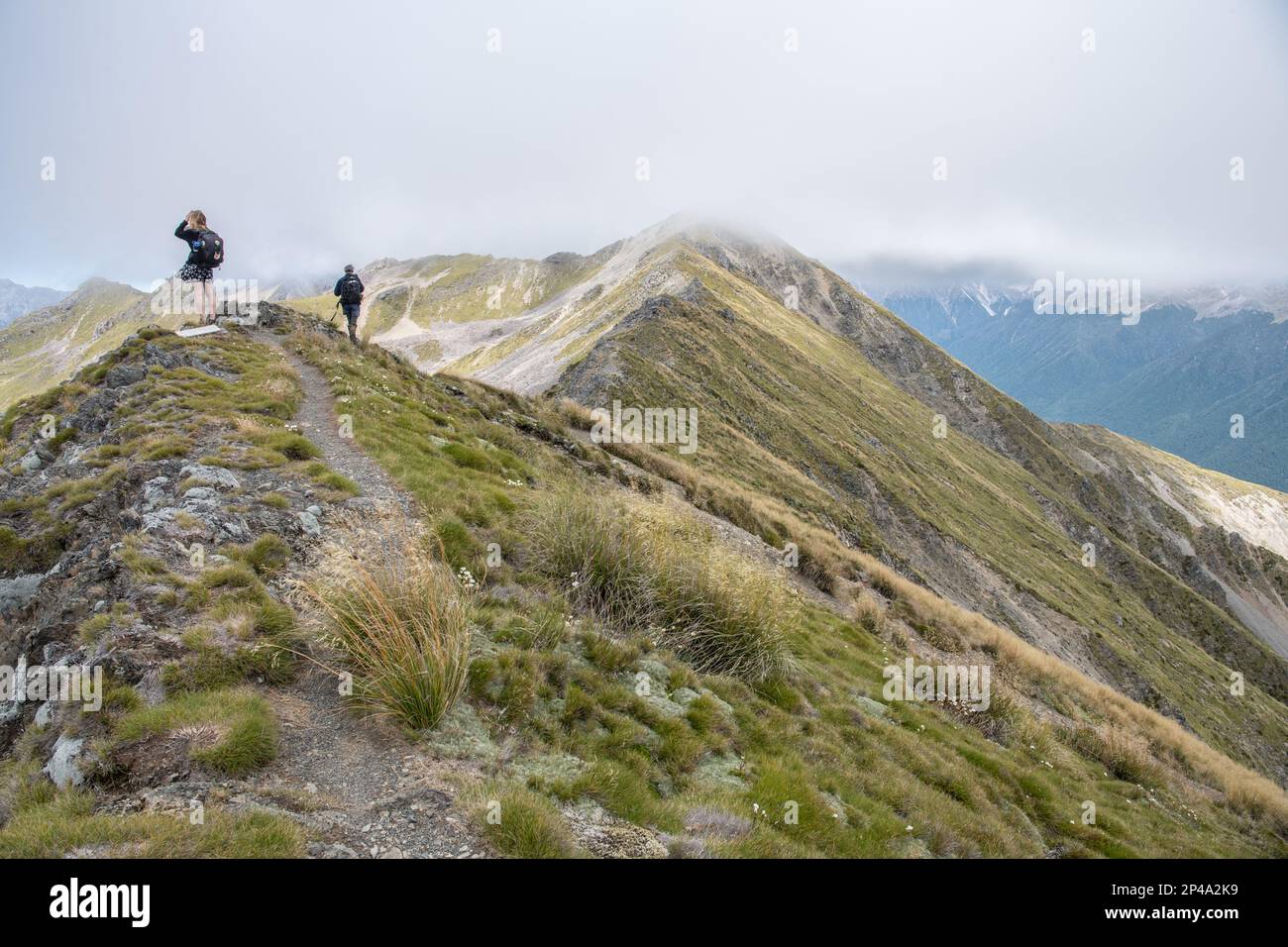 Two hikers walking a hiking trail at the top of a mountain ridge in ...