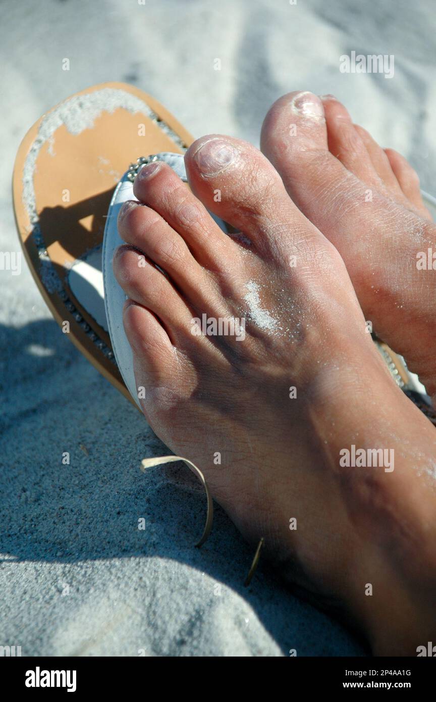 Sandals and feet in sand Stock Photo - Alamy