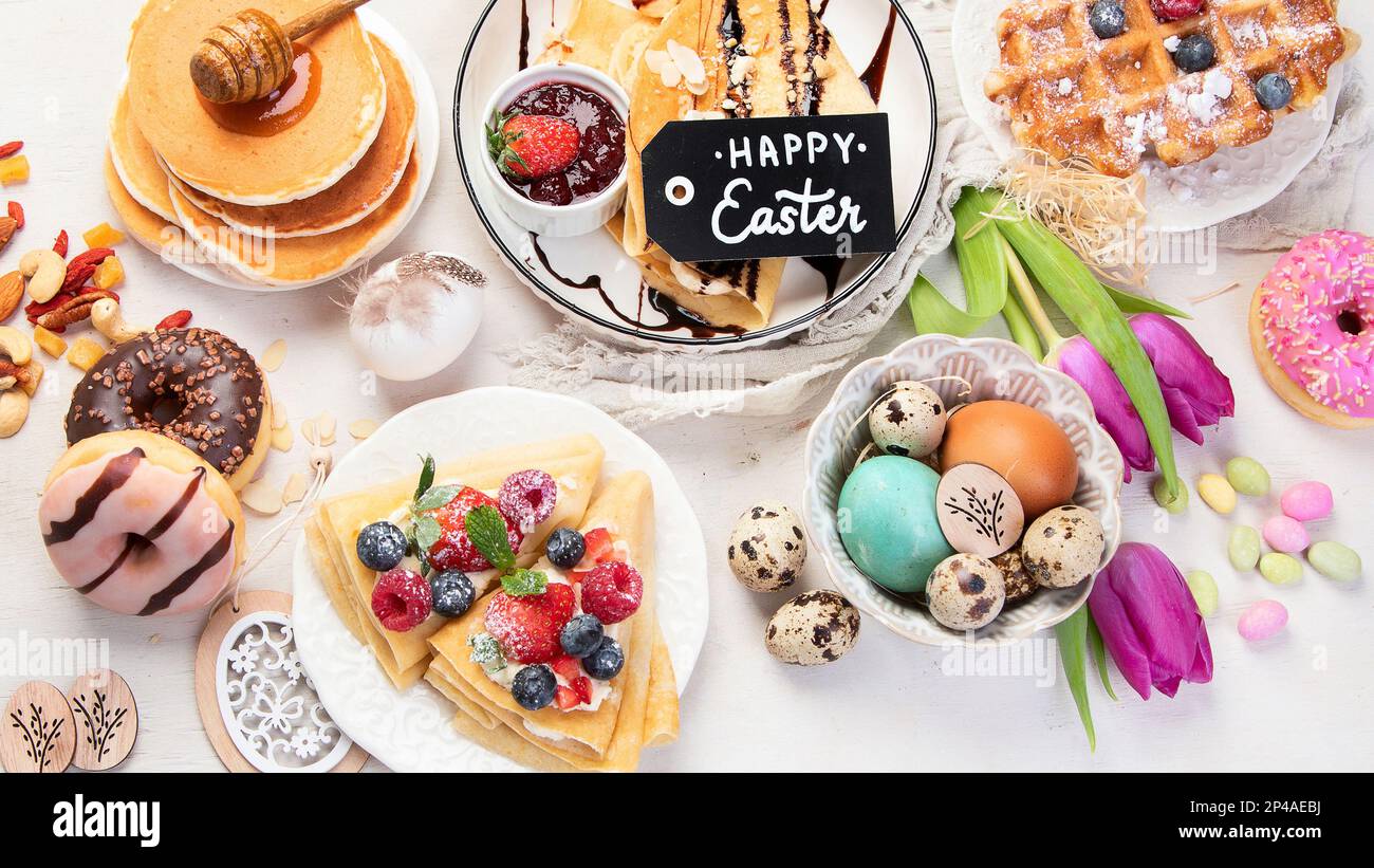 Easter sweet dessert table. Pancakes, crepes, waffles and donuts with ...
