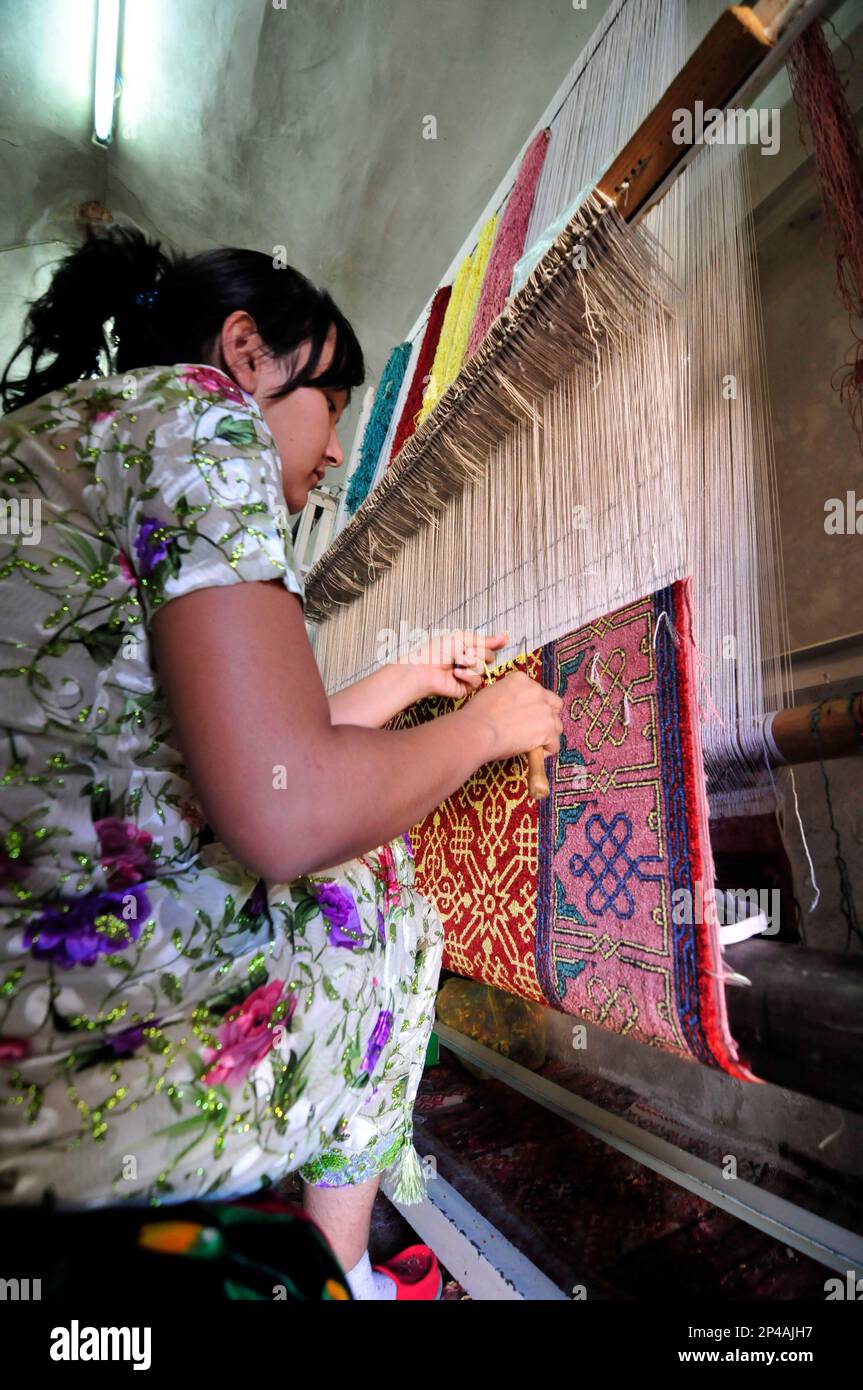 Uzbek women weaving a handmade traditional carpet in a small rug ...