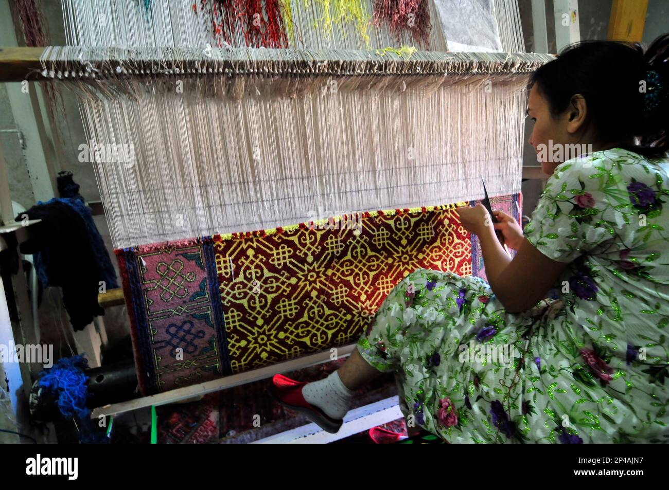 Uzbek women weaving a handmade traditional carpet in a small rug ...