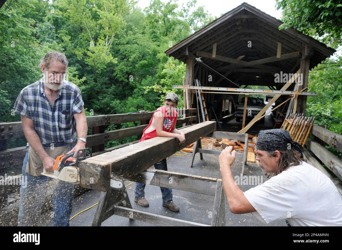Coy Parton cuts a timber to length as he and Isaiah Kemp and Ken ...