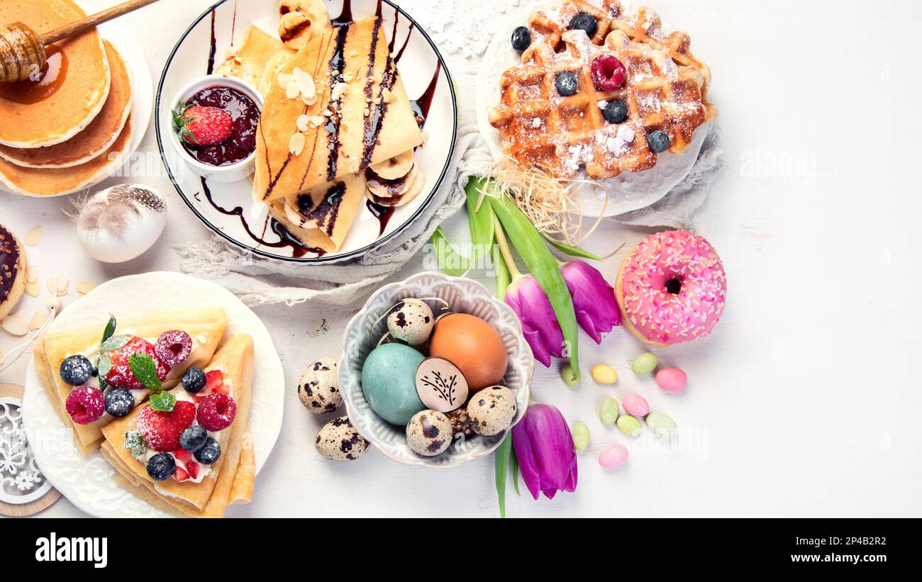 Easter sweet dessert table. Pancakes, crepes, waffles and donuts with ...