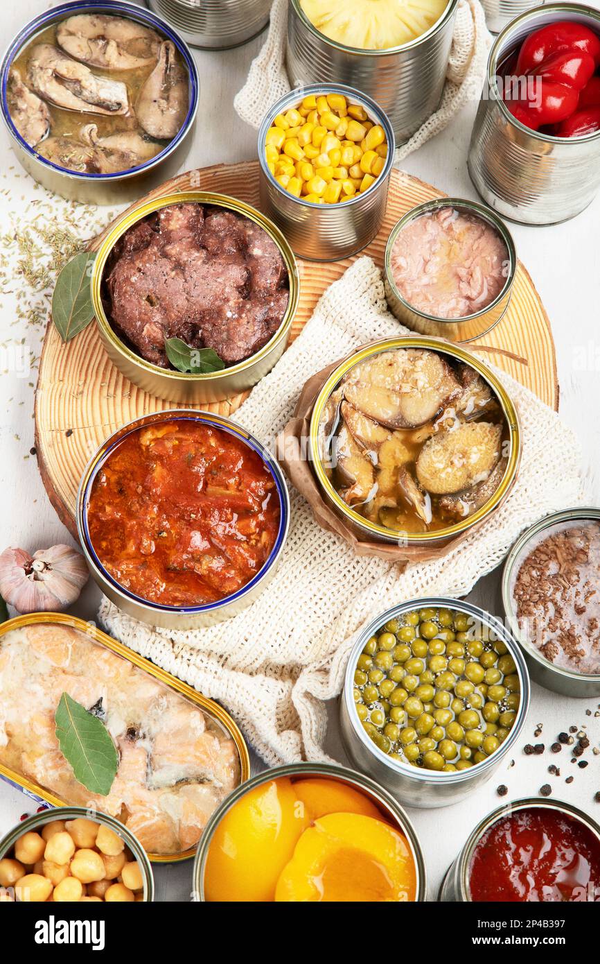 Various canned vegetables, meat, fish and fruits in tin cans. On a ...