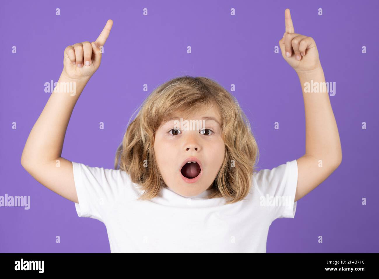 Surprised child pointing up finger on studio background. Shocked kid ...
