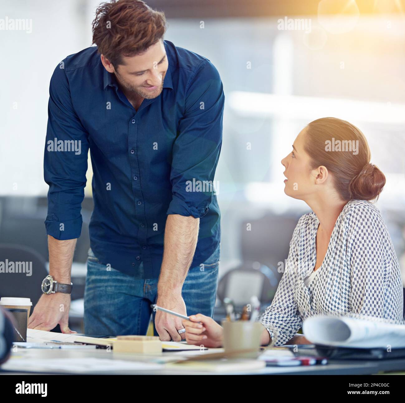 This office runs on positivity. two coworkers talking together in an office Stock Photo - Alamy