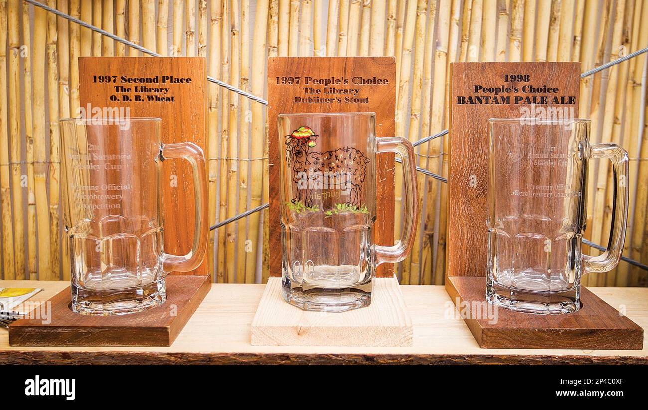 A collection of trophy mugs and awards line a shelf in the brewery of ...