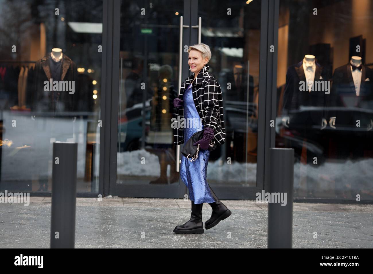 Beautiful middle aged fashion model walking next to clothing store ...