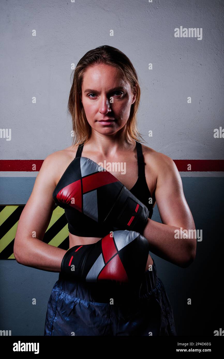 Female boxer wearing boxing gloves looking at camera while posing ...