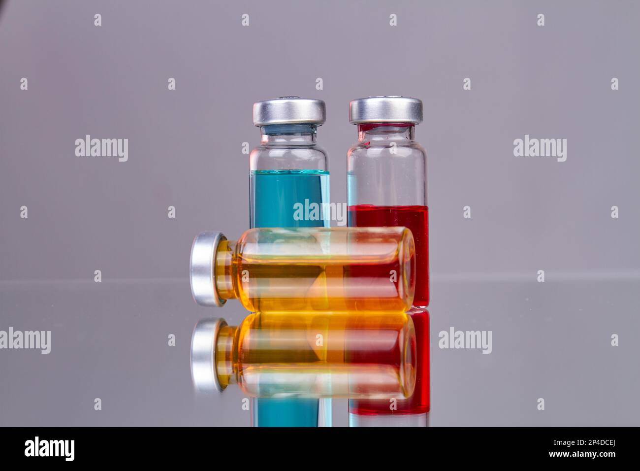 Collection of glass drug vials with colored medicine. Reflective ...