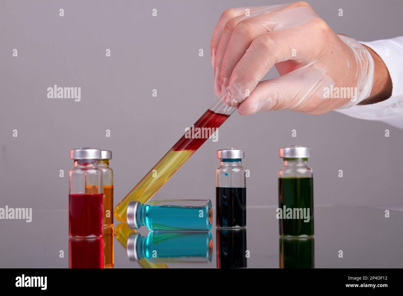 Doctors hand holding test tube with blood. Drug vials with colored ...