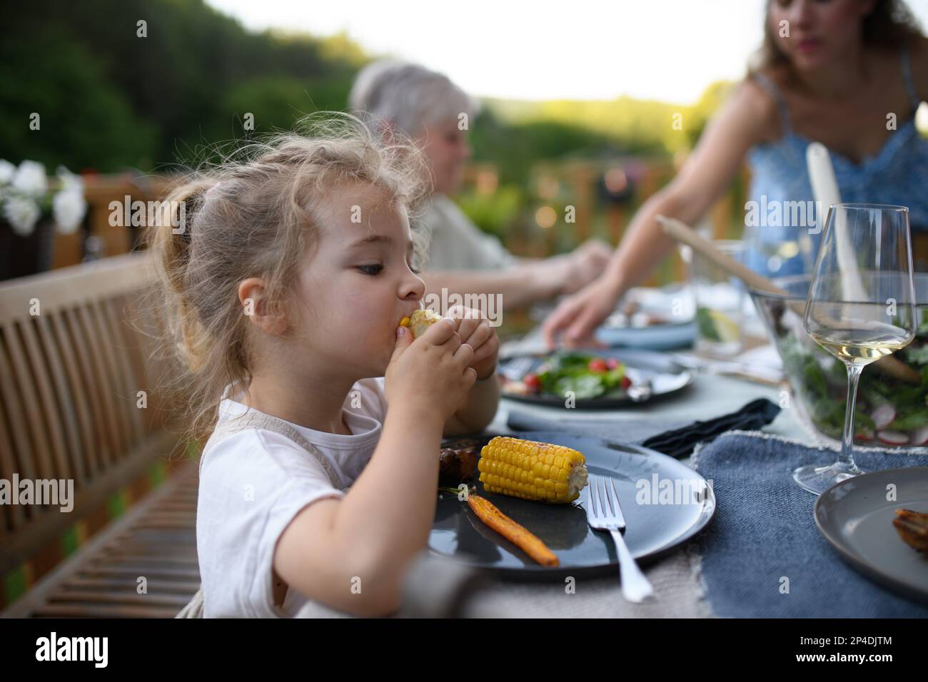 Family eating at barbecue party dinner on patio, little girl eating ...