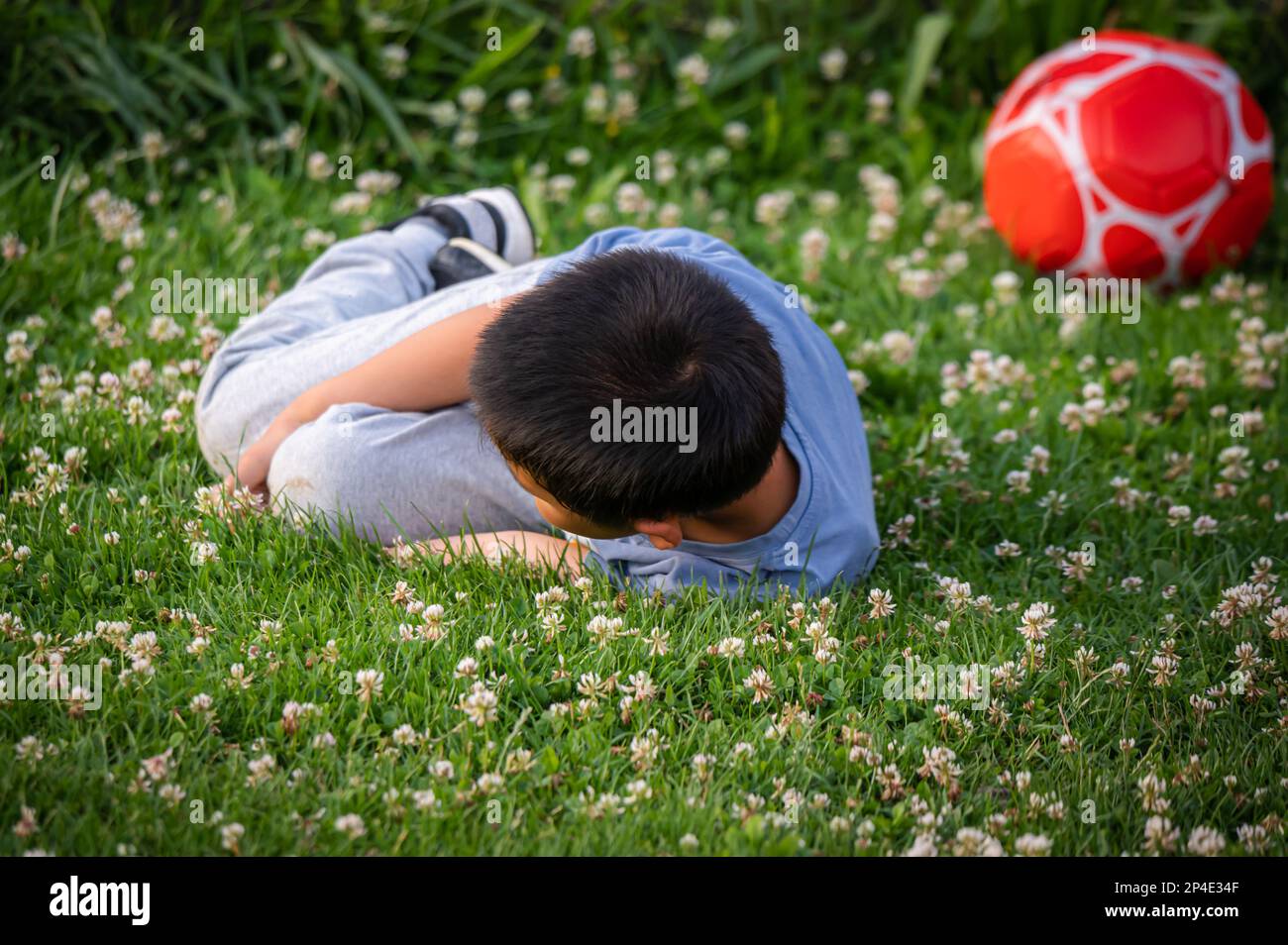 Child playing football. One Asian boy falling down in spring Stock ...