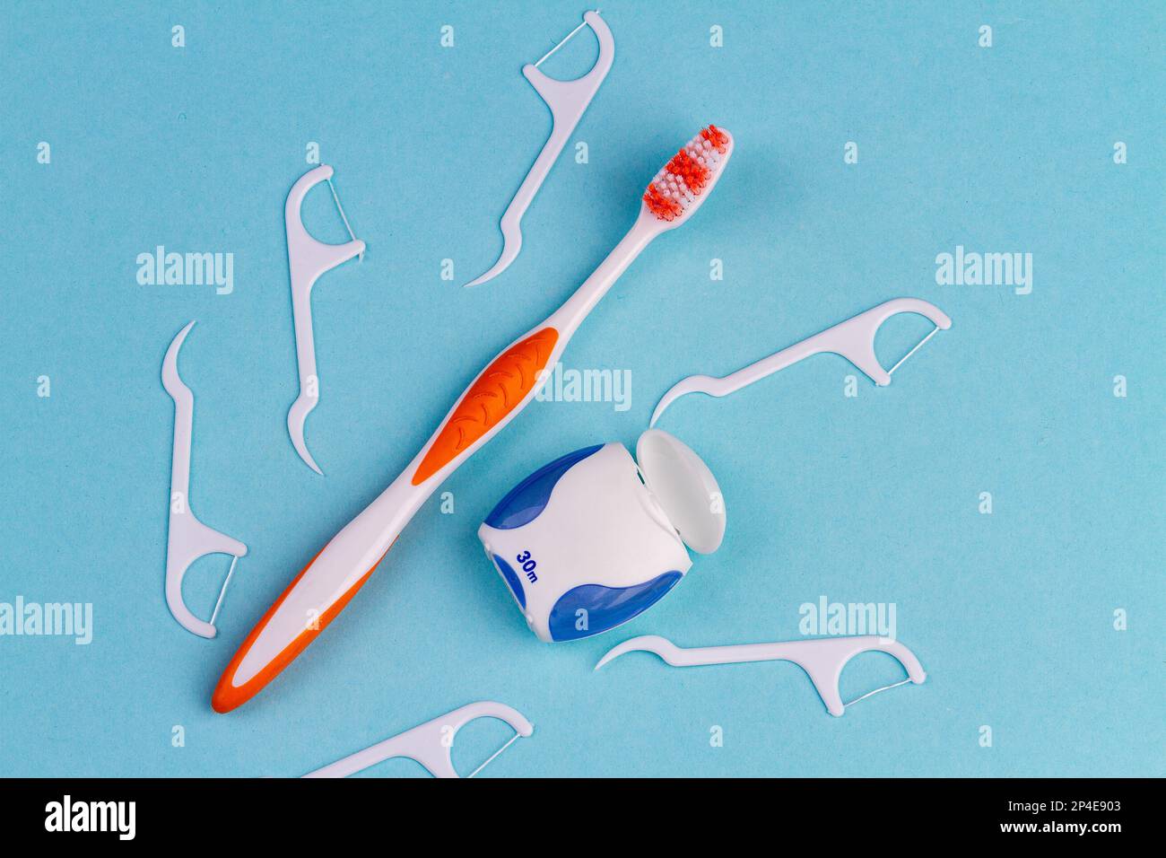 Toothbrush with dental floss picks and thread. Top view blue background ...