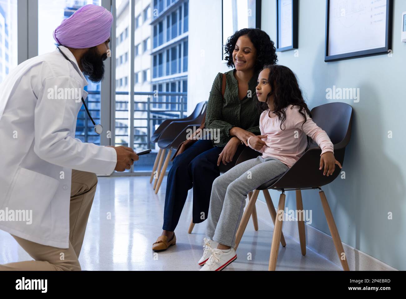 Sikh male doctor in turban talking with daughter and mother in hospital ...