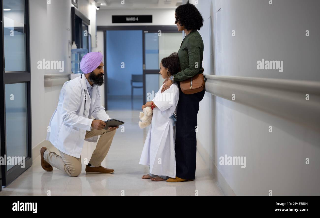Sikh male doctor in turban talking with daughter and mother embracing ...