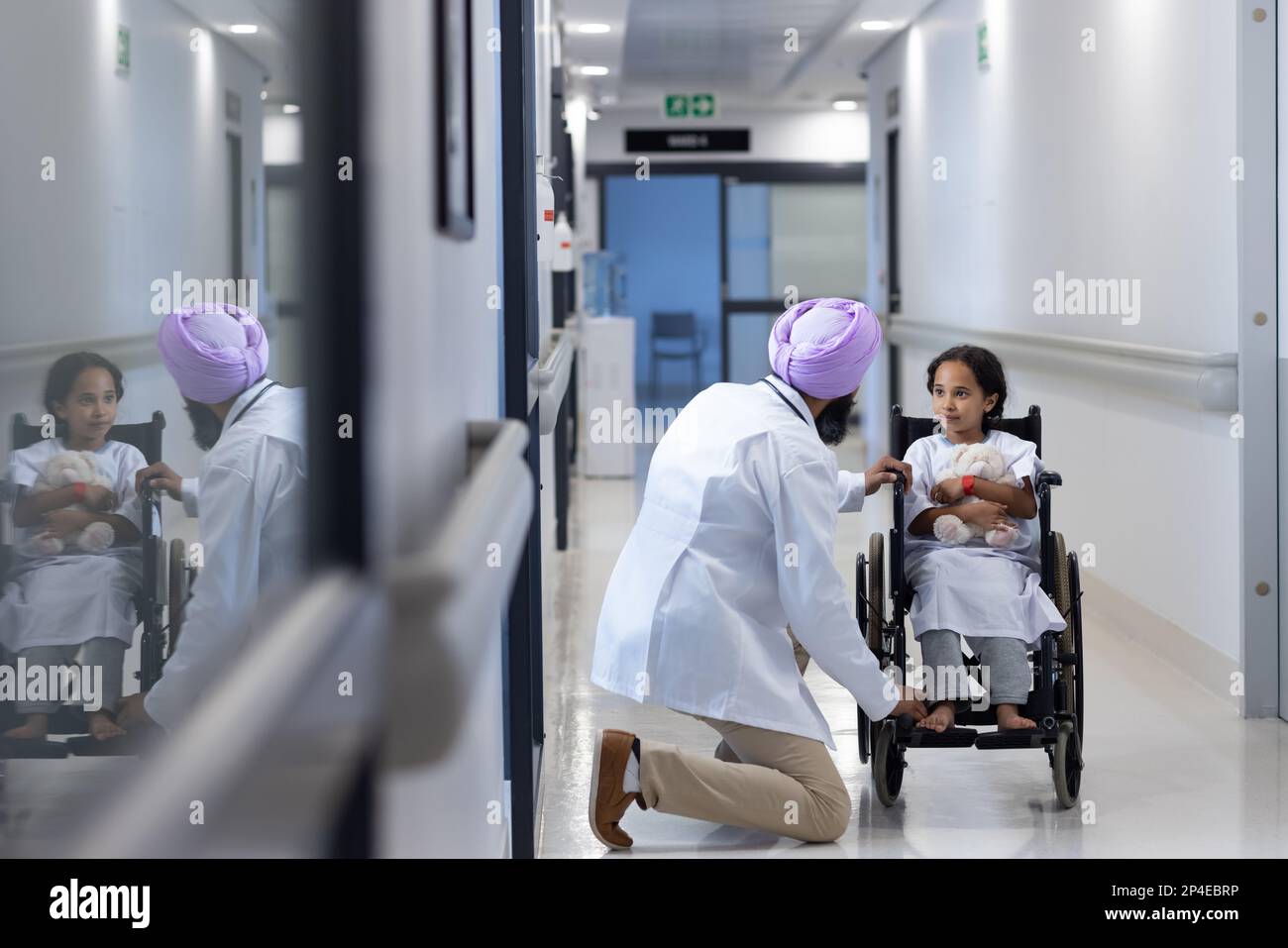 Sikh male doctor in turban with girl sitting in wheelchair in hospital ...