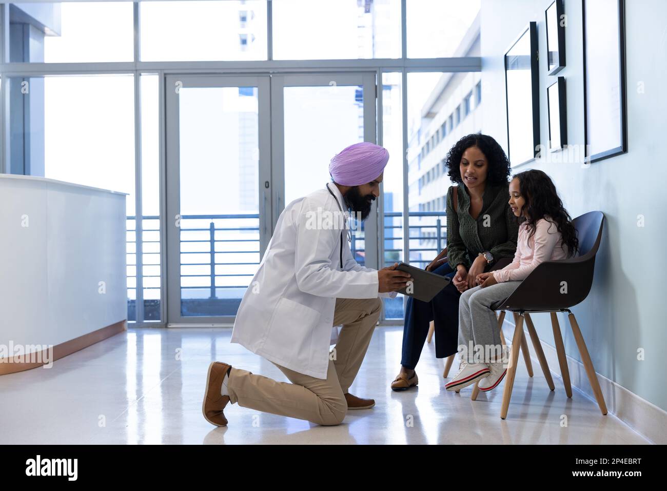 Sikh male doctor in turban talking with daughter and mother in hospital ...