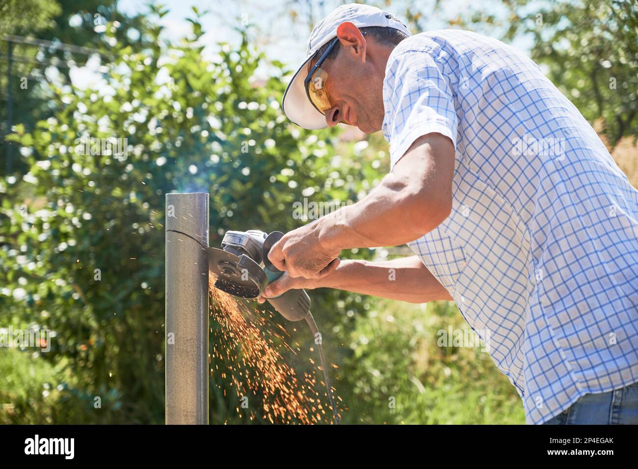Worker cutting metal pole with grinder for installing solar panels ...