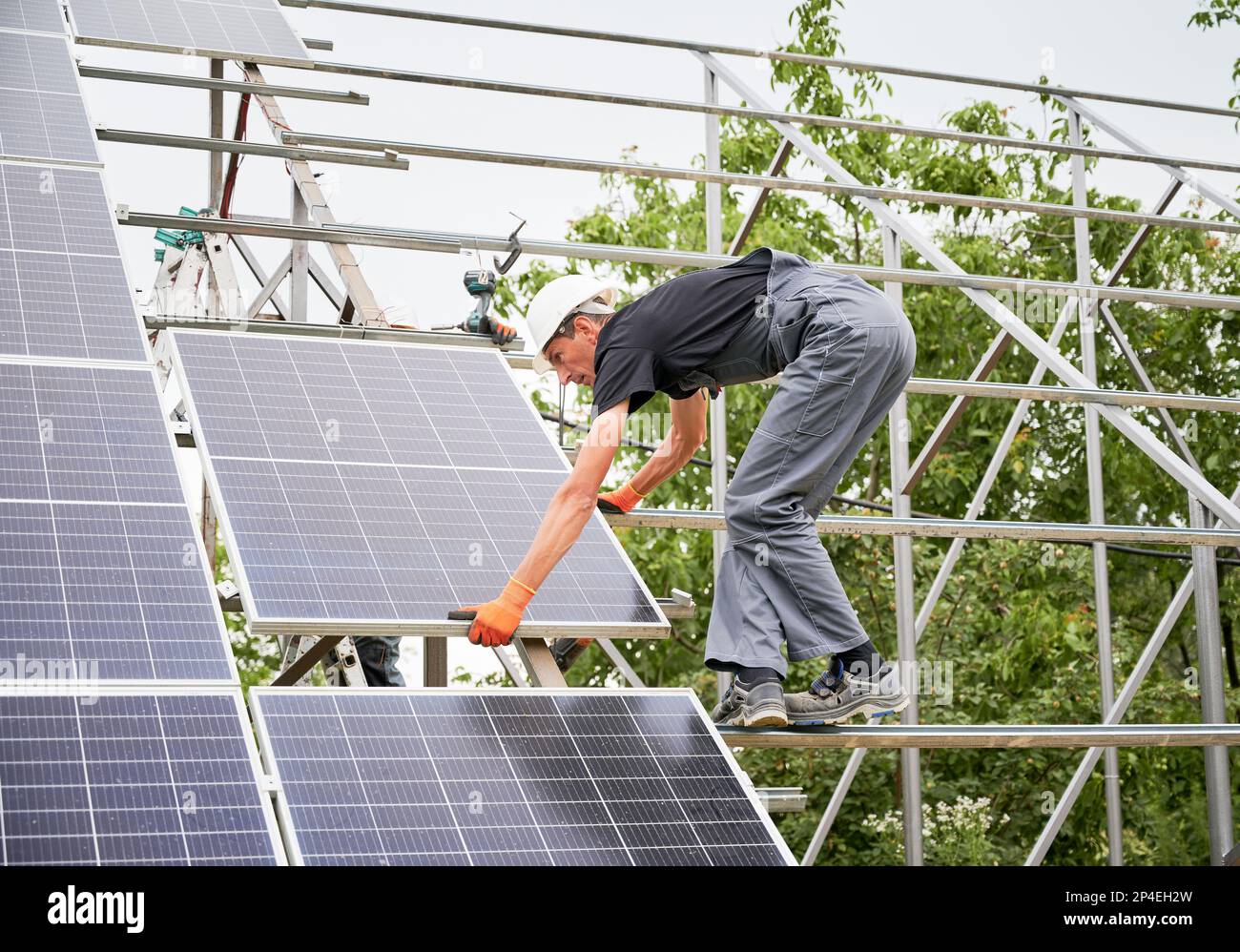 Worker installing solar panels on metal beams. Man in helmet and ...
