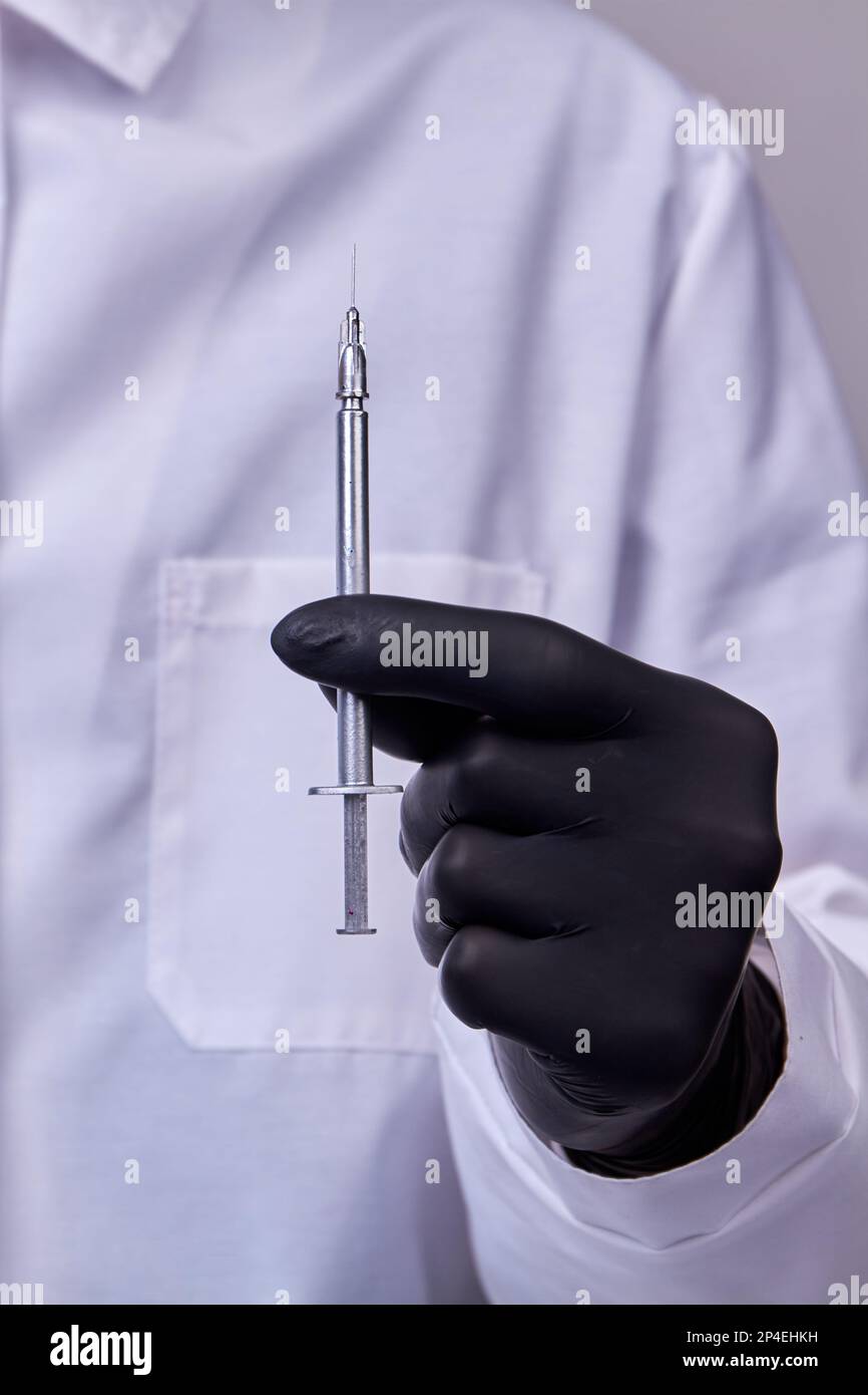 Surgeon hand in black glove holding cosmetic syringe. Clenching with ...