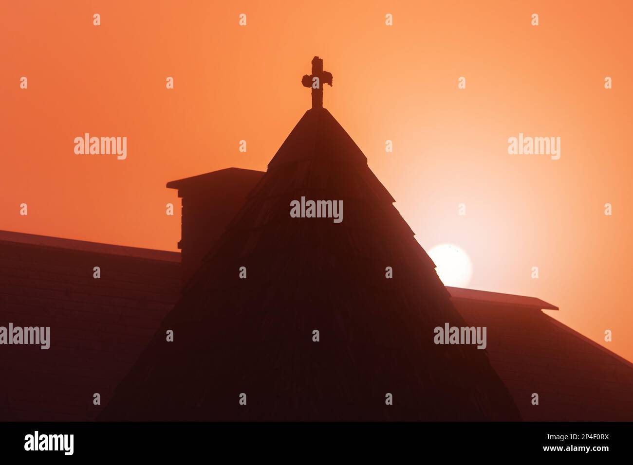 Dawn and rising sun behind the medieval church roof in Bohinj ...