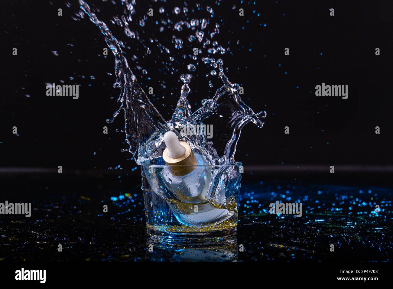 Perfume bottle falling in a glass cup with water splashes. Isolated on ...