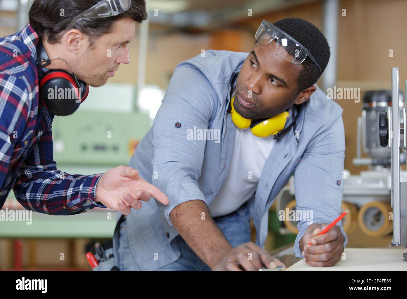 two carpenters with electric drill drilling wood plank at workshop ...