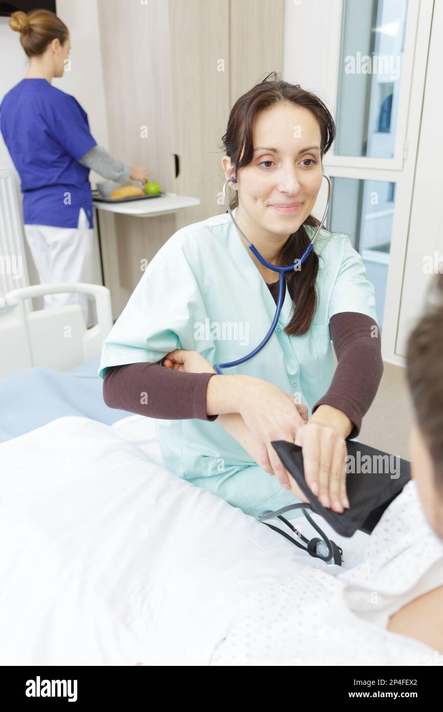 nurse taking pressure of young-male patient in hospital bed Stock Photo ...