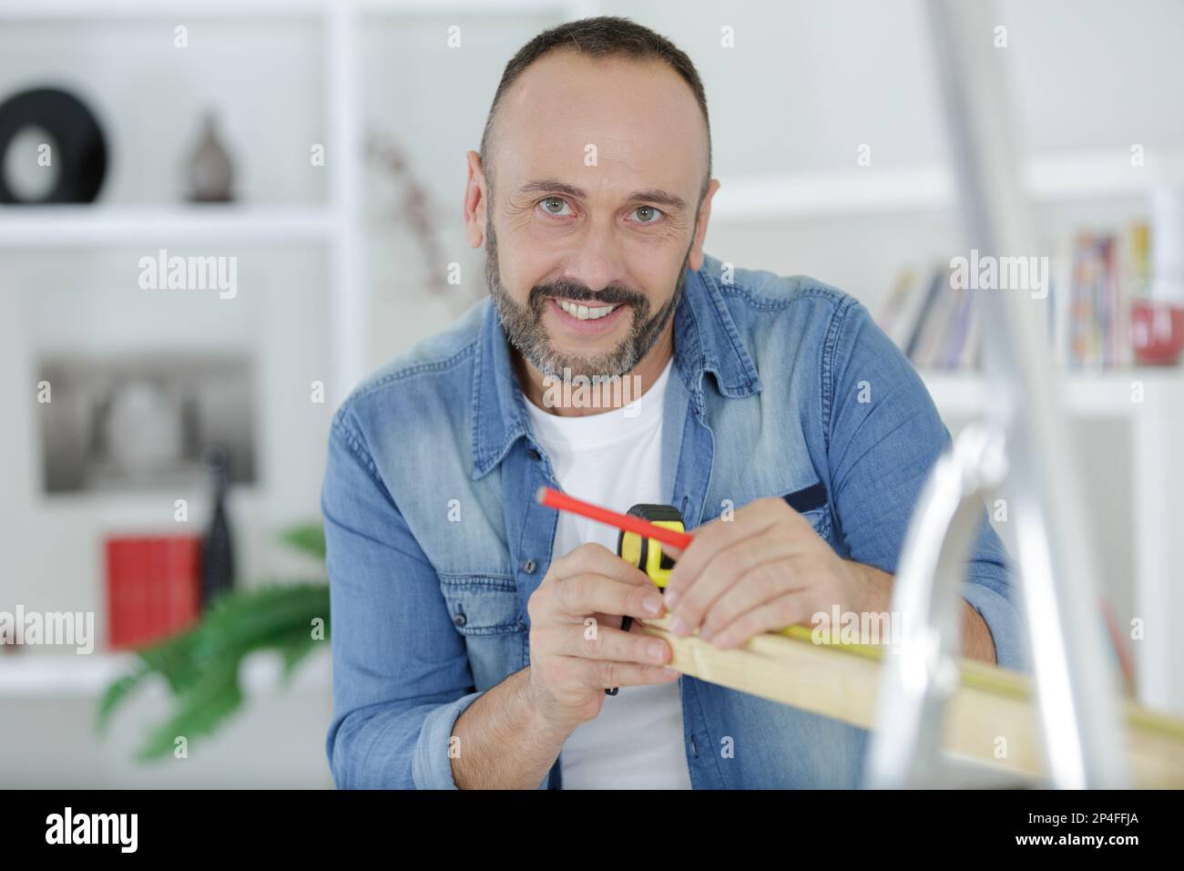 man measuring wood piece for furniture assembling Stock Photo - Alamy