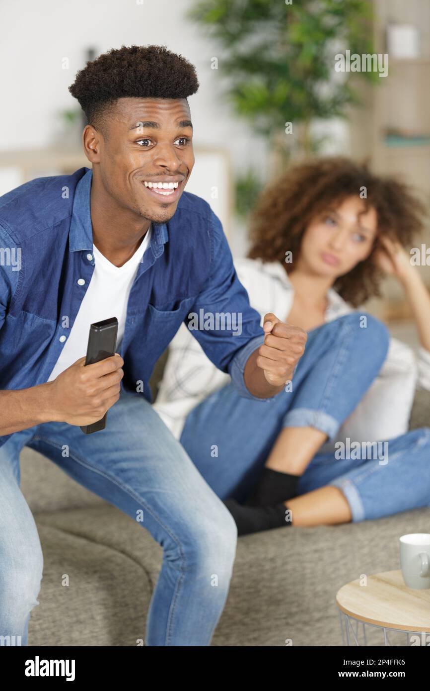 girl is bored while excited boyfriend watches tv Stock Photo - Alamy
