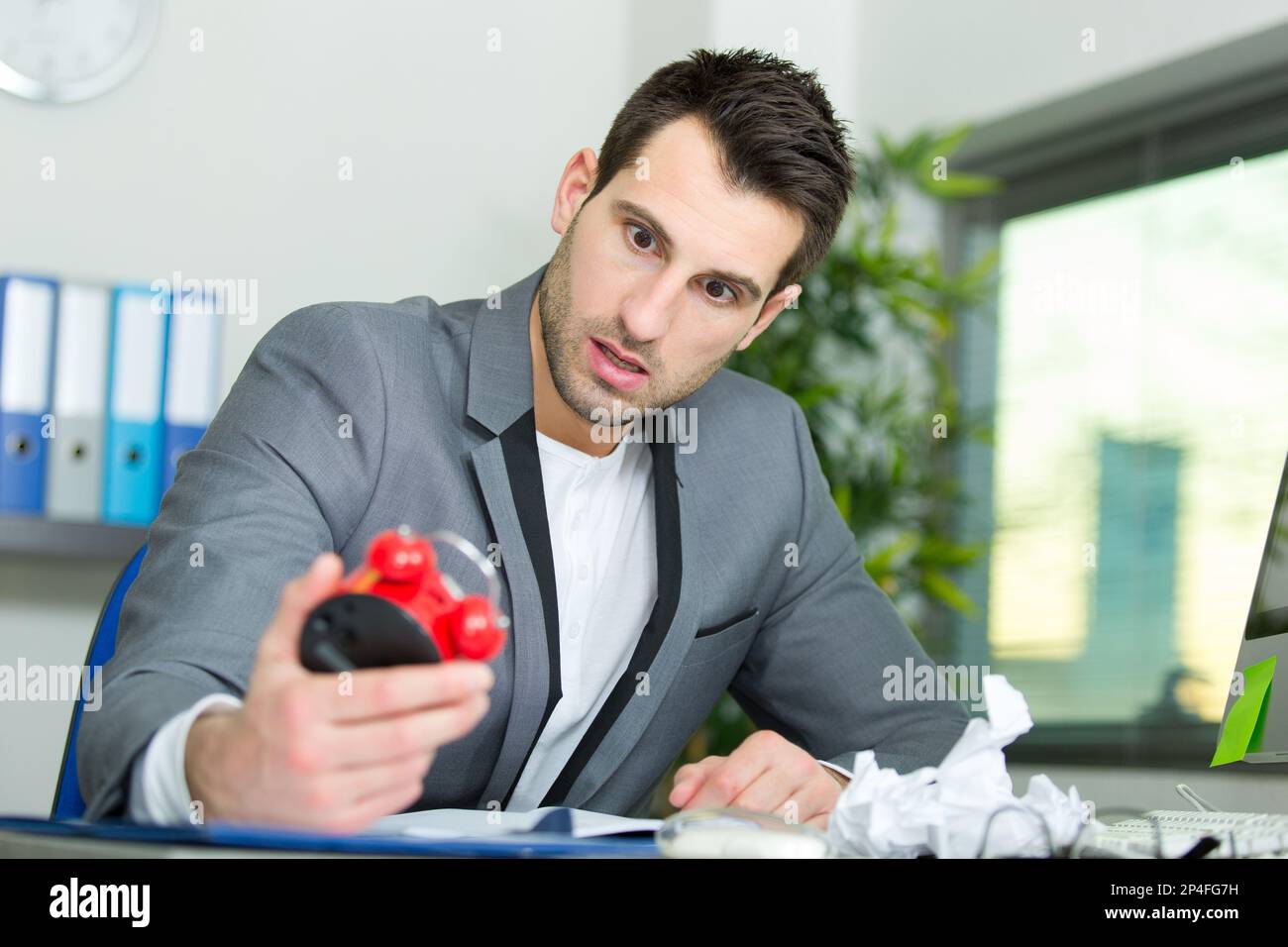 male office worker shock expression looking at alarm clock Stock Photo ...