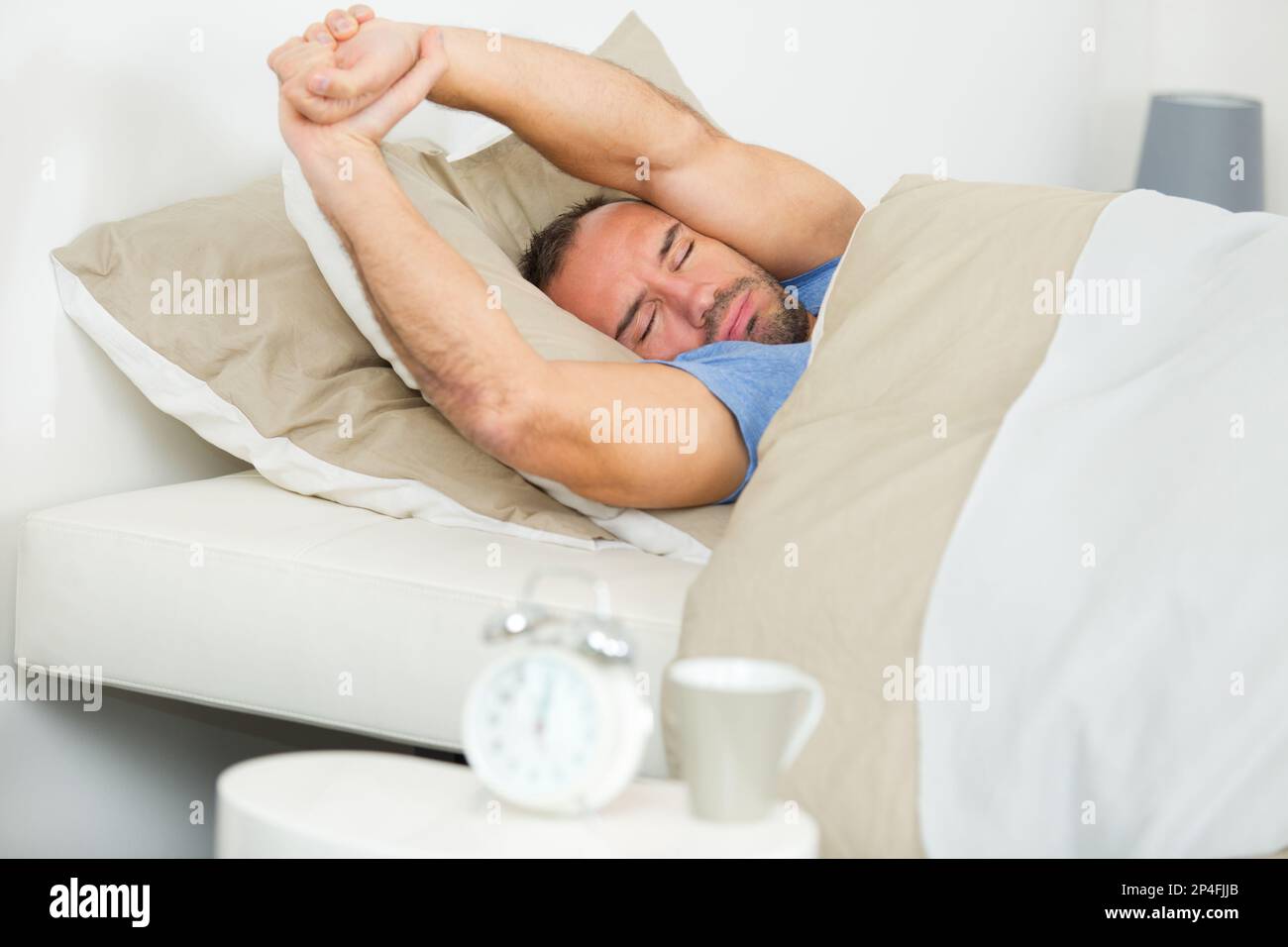 man in bed stretching arms over his head Stock Photo - Alamy