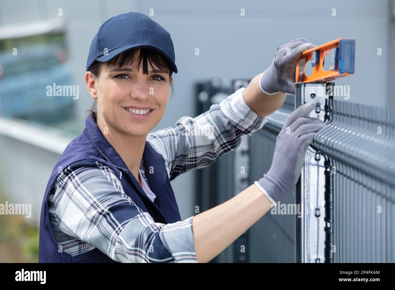 fence construction female worker check the level of metal post Stock ...