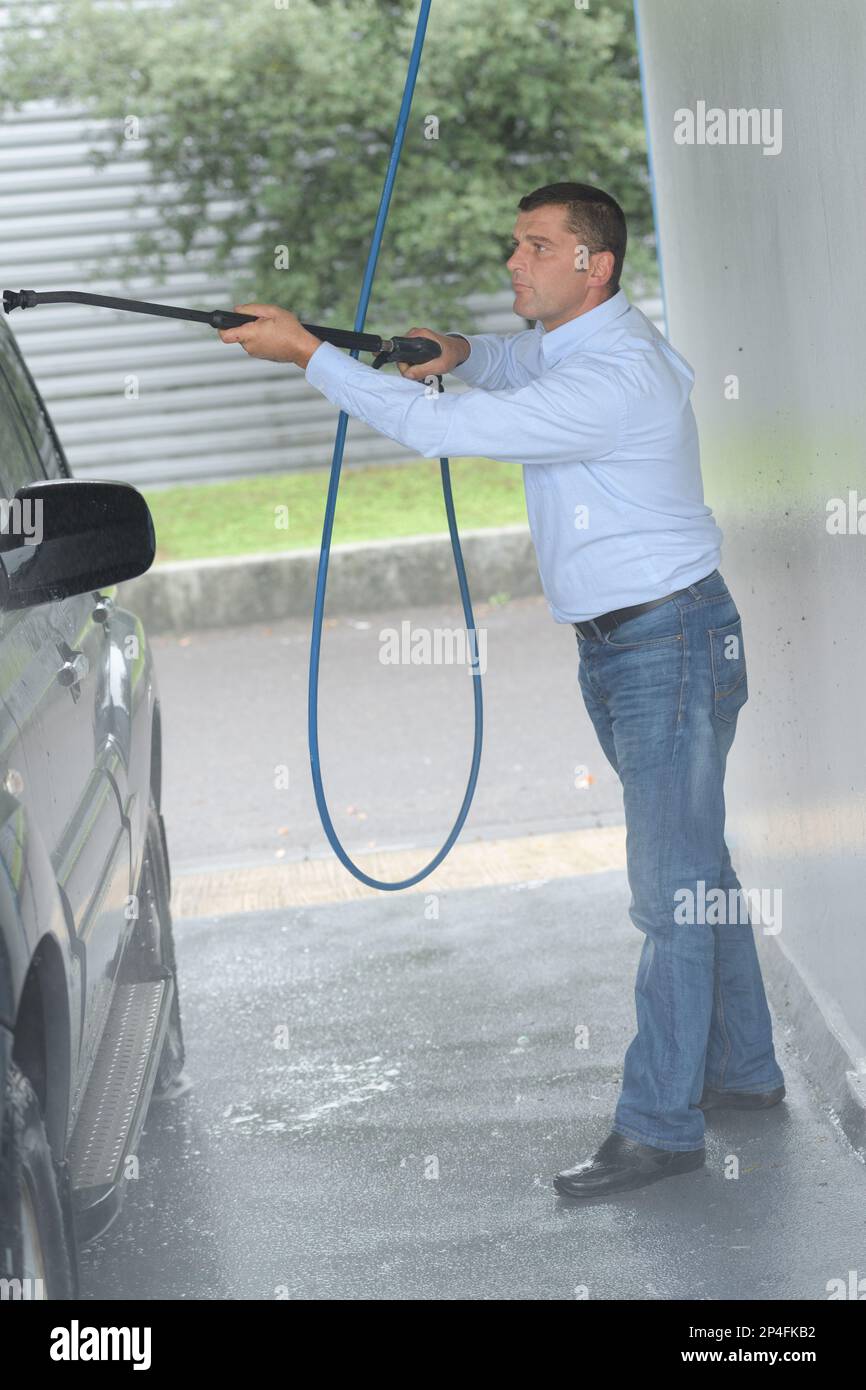 man with high pressure water jet washing car Stock Photo - Alamy