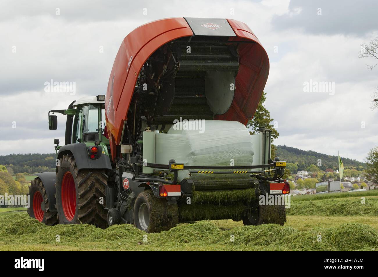 Cow in a baler and wrapper, wrapping silage round bales in plastic ...