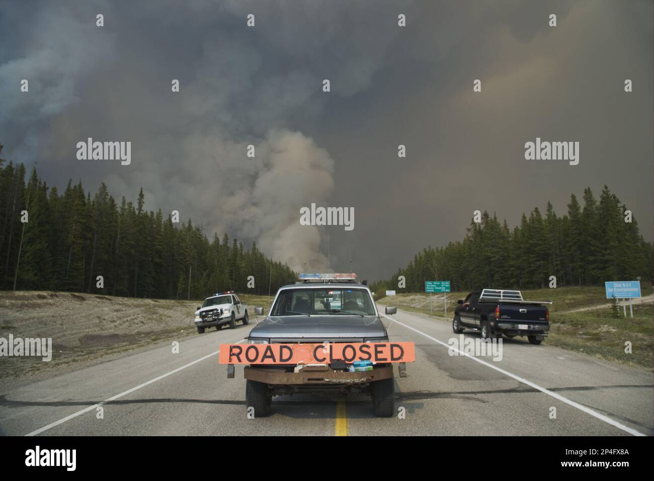 Forest fire, controlled burn beside road, Road Closed sign on pickup ...
