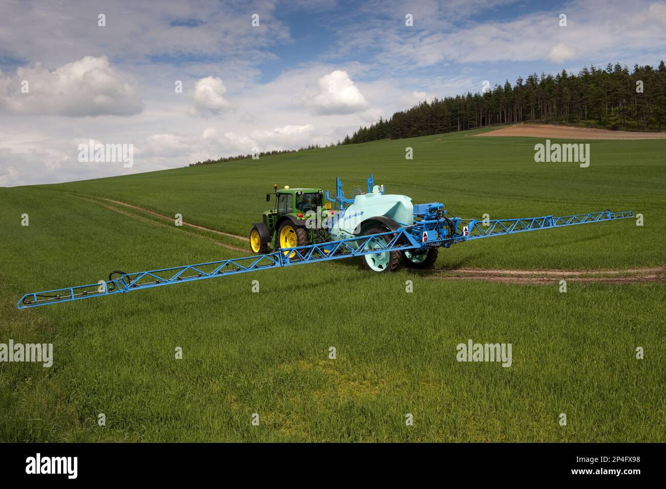 Tractor with sprayer, spraying spring barley with herbicide, England ...