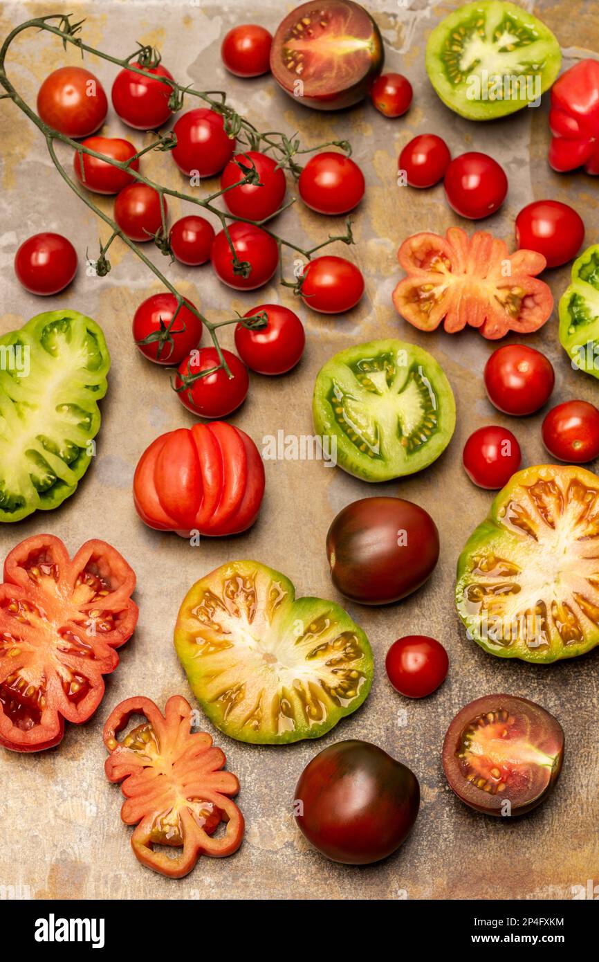 Different types of tomato, tomato halves and a sprig of cherry tomatoes ...
